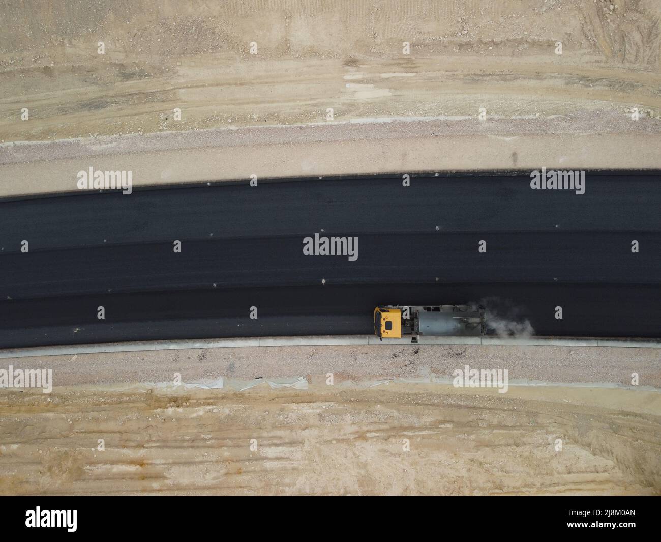 yellow truck pouring bitumen over a new road. Aerial drone shot. Road ...