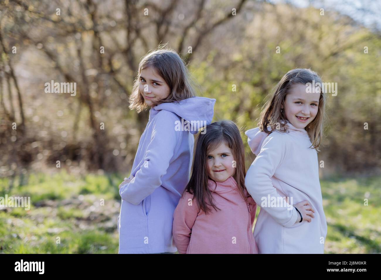 Three little sisters looking at camera in spring nature together Stock ...