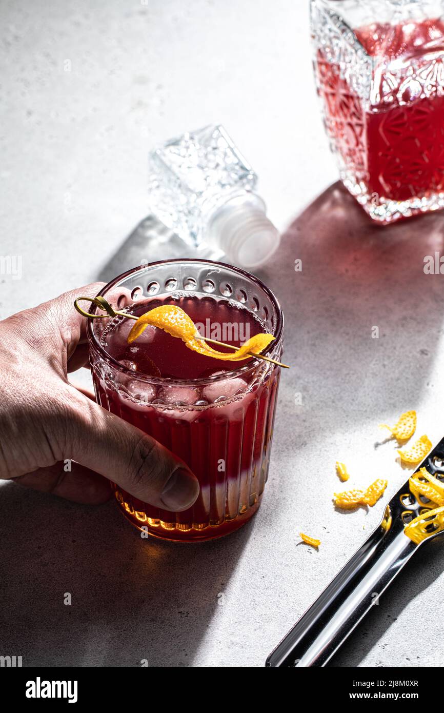Iced cold red lemonade short in hand over concrete table background ...