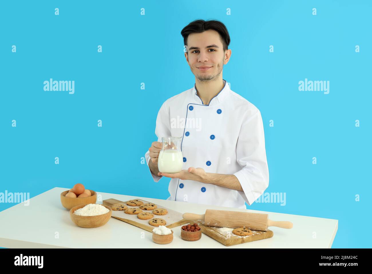 Concept of cooking, young man chef on blue background Stock Photo - Alamy