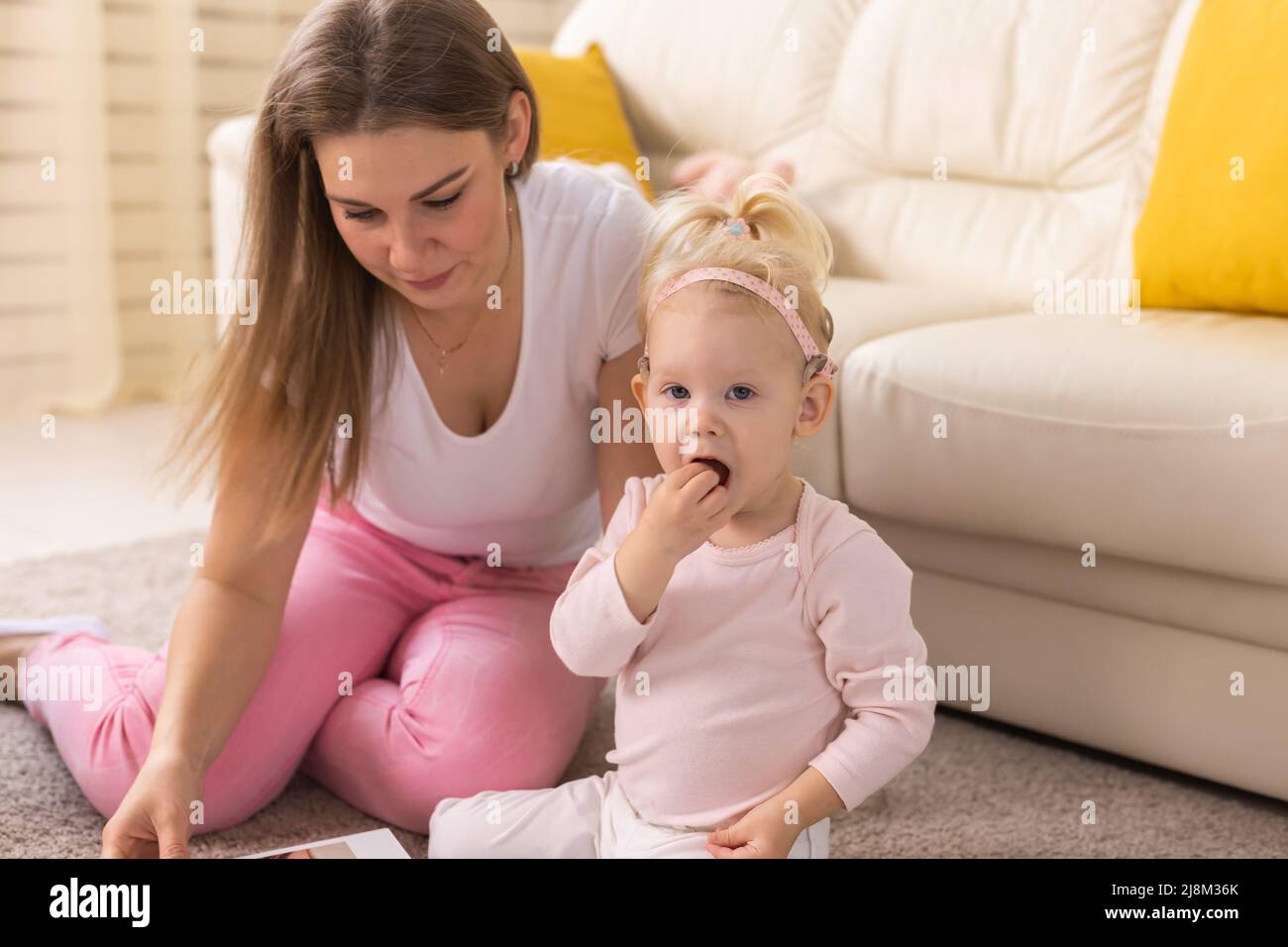 Happy child girl with cochlear implant having fun with her mother ...