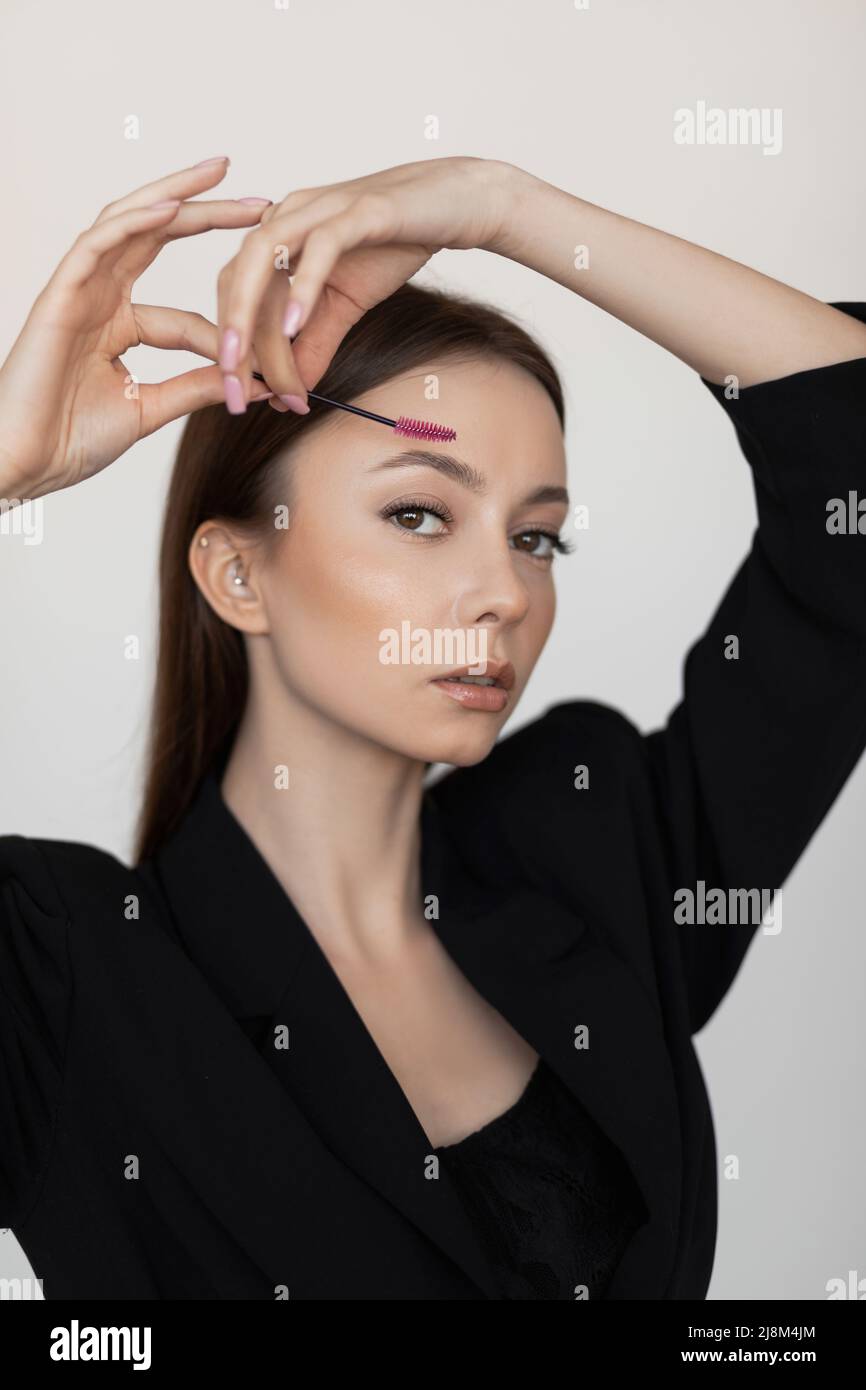 Vertical woman face look at camera trimming and correcting, brushing ...