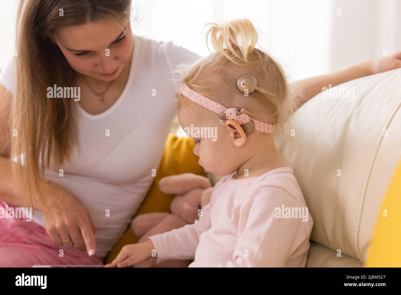 Child girl with cochlear implant with her mother at home. Hear ...