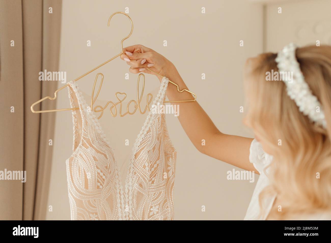 Elegant woman hold wedding white dress with embroidered pattern on ...