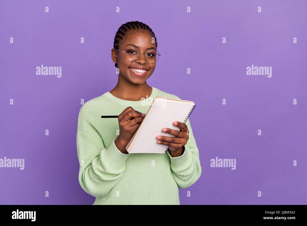 Photo of charming young female working as journalist writing an essay ...