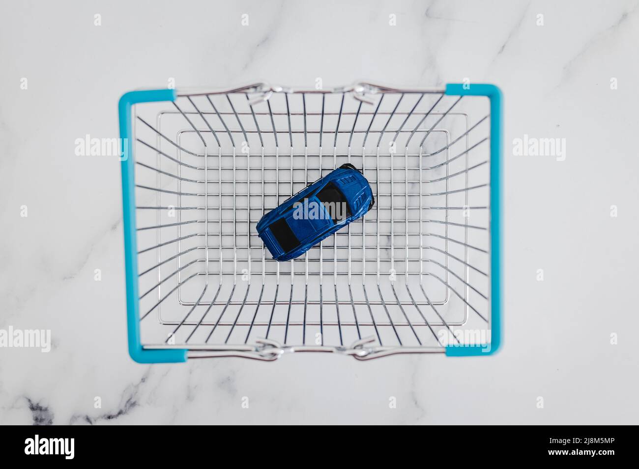 toy car inside of shopping basket over white marble background, concept ...