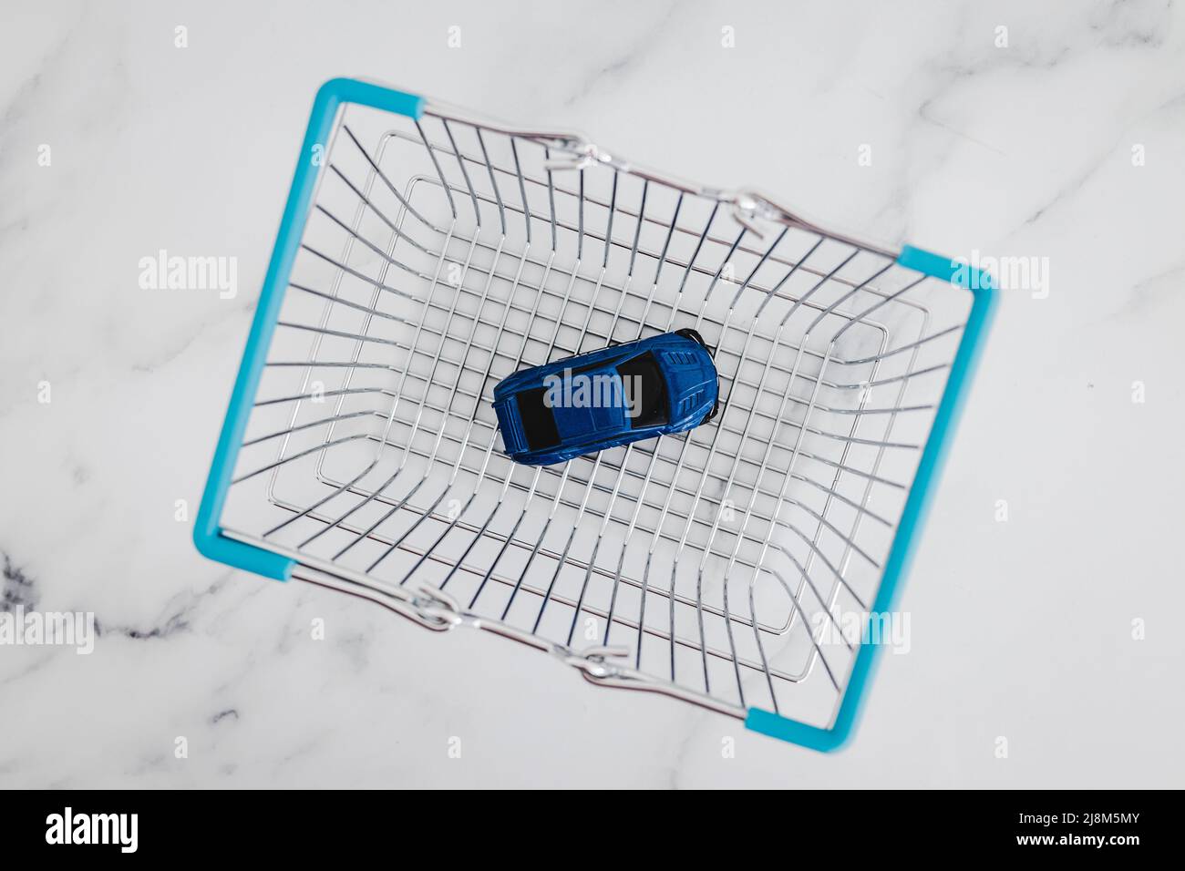 toy car inside of shopping basket over white marble background, concept ...