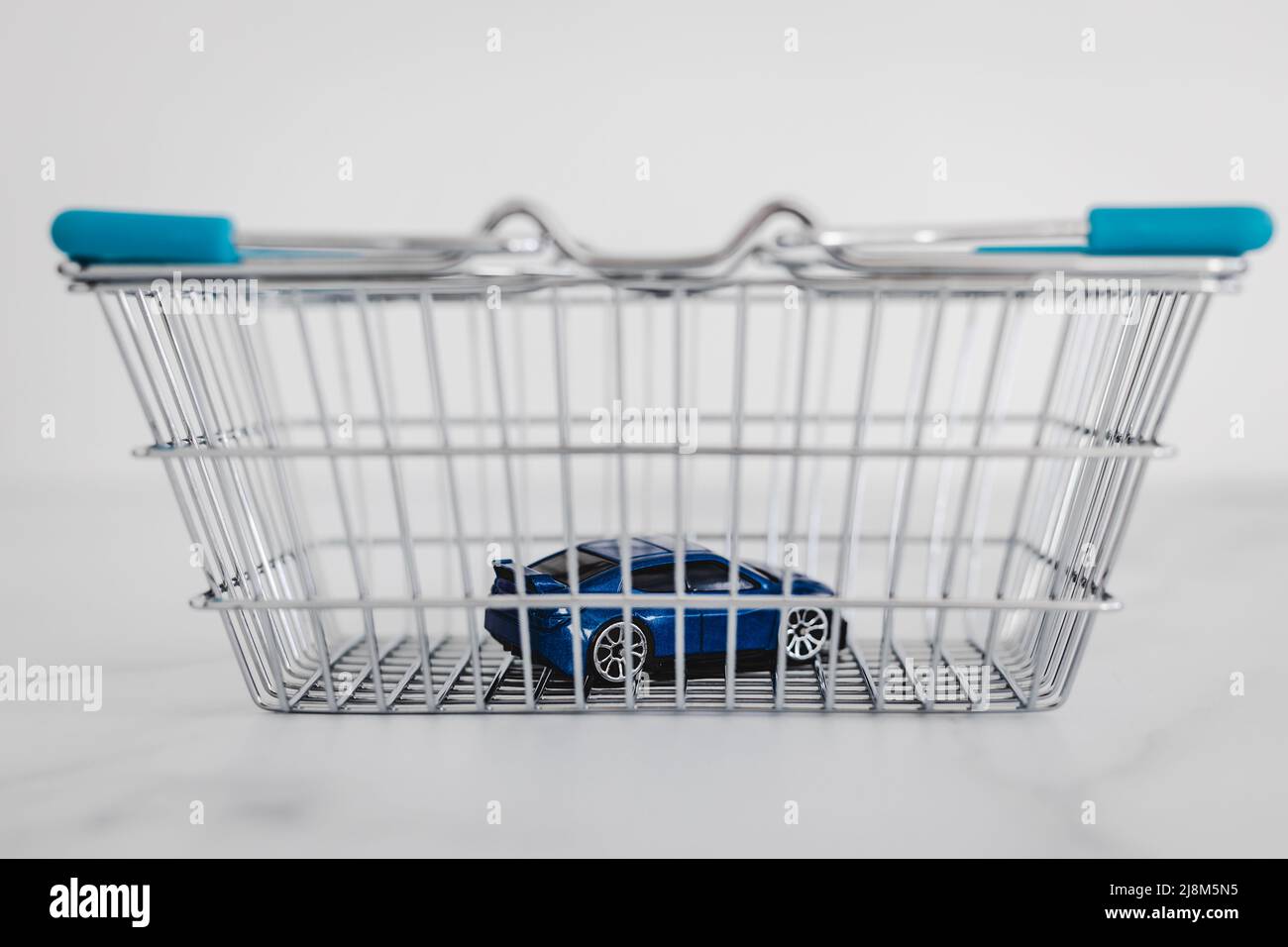 toy car inside of shopping basket over white marble background, concept ...