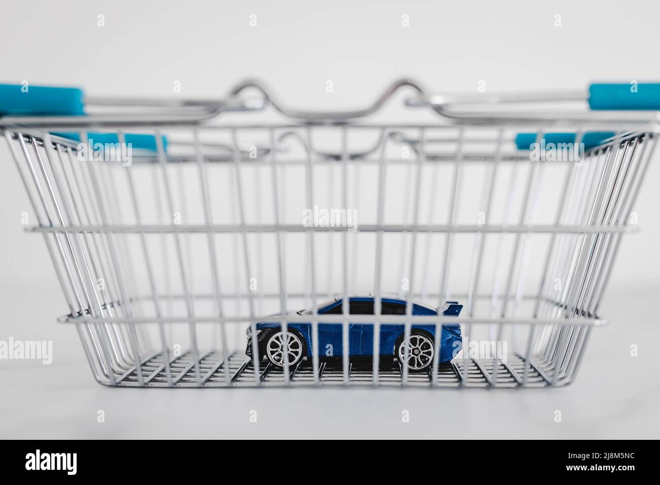 toy car inside of shopping basket over white marble background, concept ...
