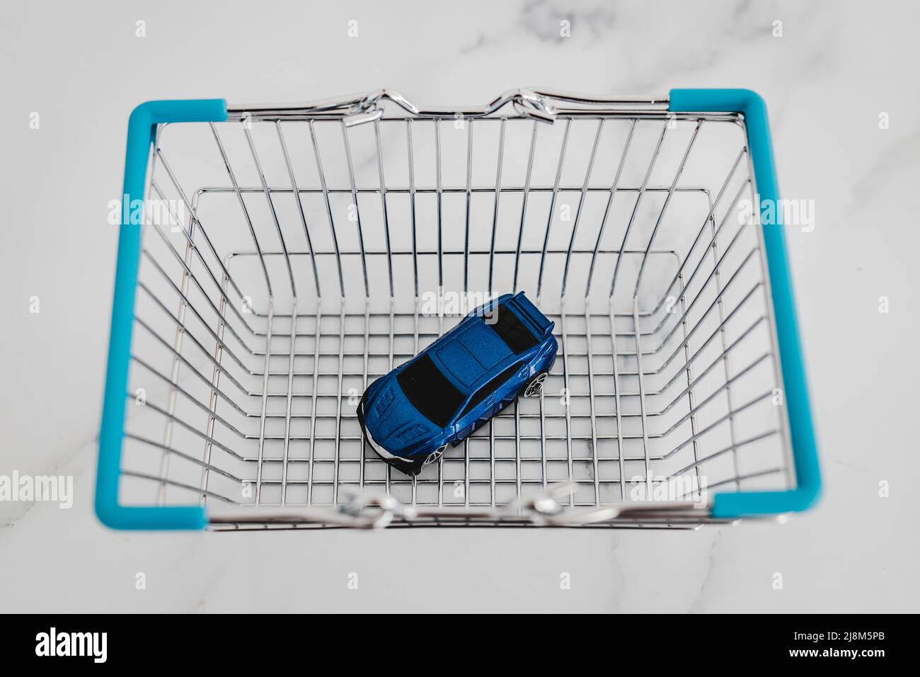 toy car inside of shopping basket over white marble background, concept ...