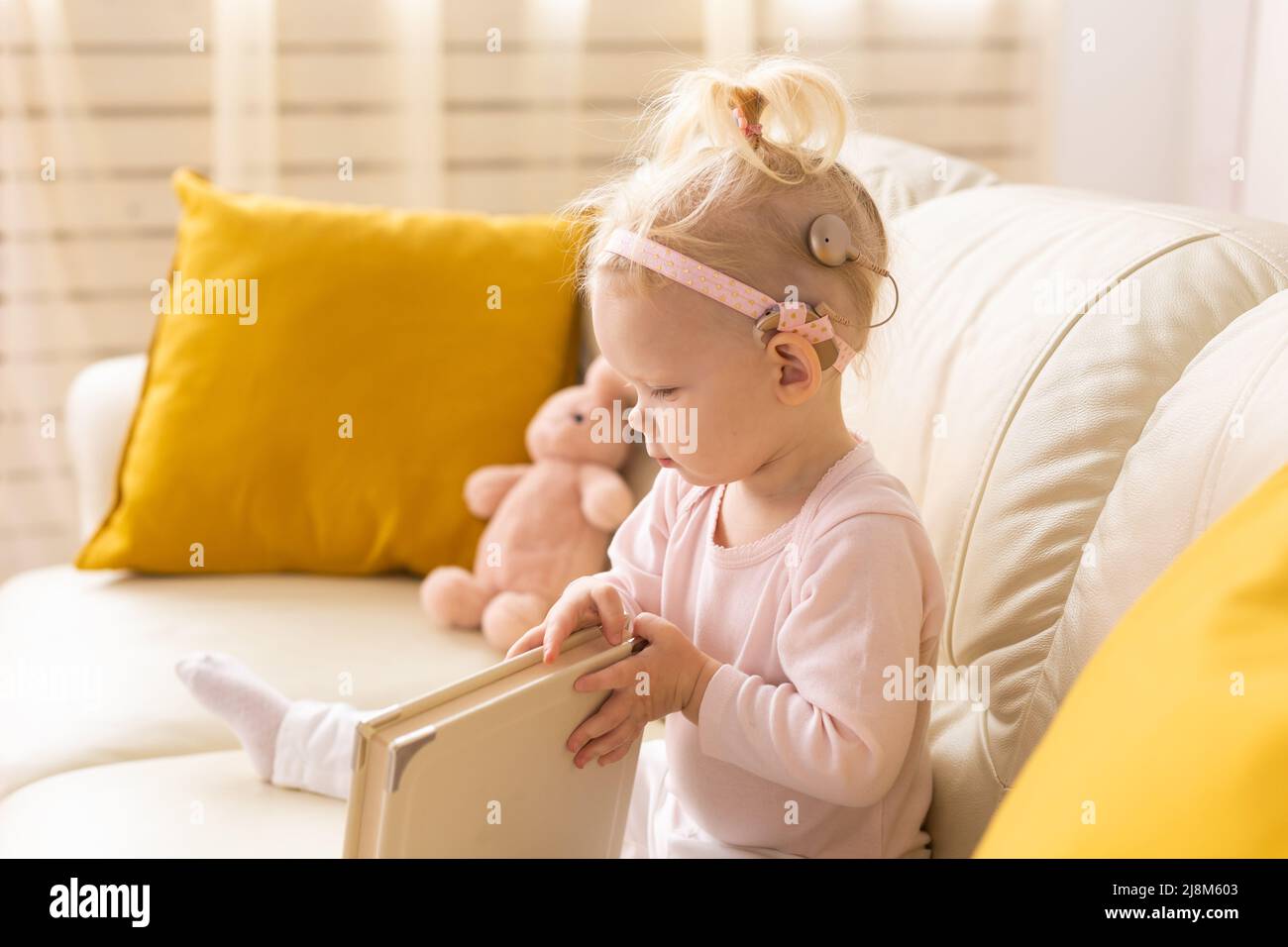 Baby with cochlear implants at home. Deafness and medical technology ...