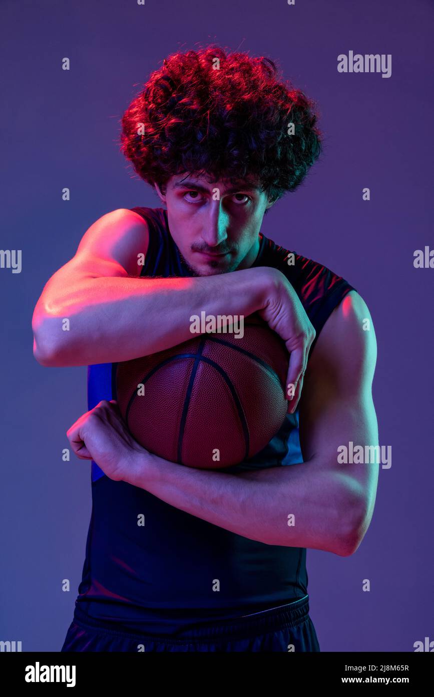 Portrait of young muscular basketball player looking at camera isolated ...