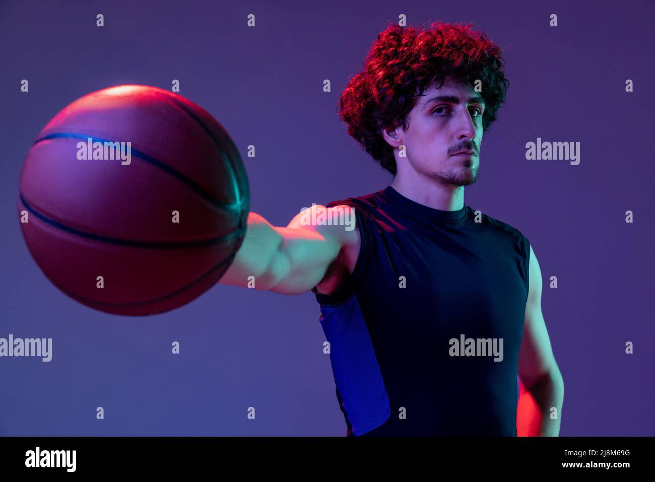 Portrait of young muscular basketball player looking at camera isolated ...