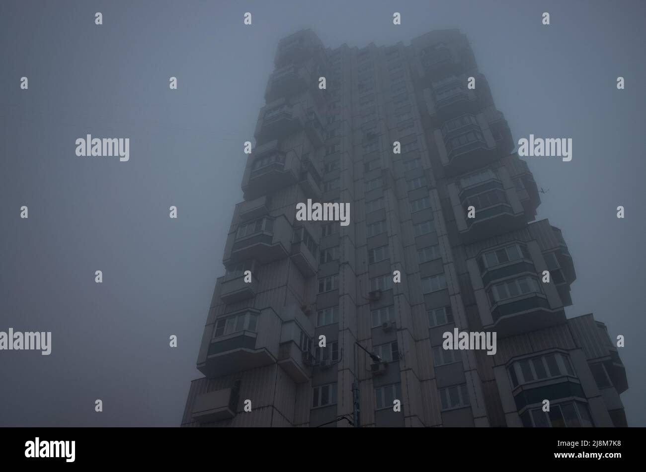 Tall residential building in the form of a tower, immersed in a misty ...
