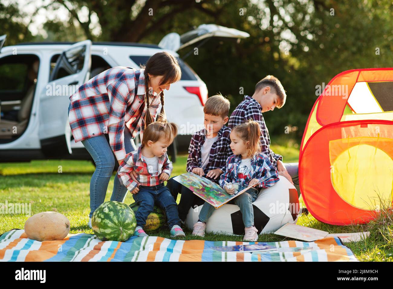 Family spending time together. Mother reading book outdoor with kids ...