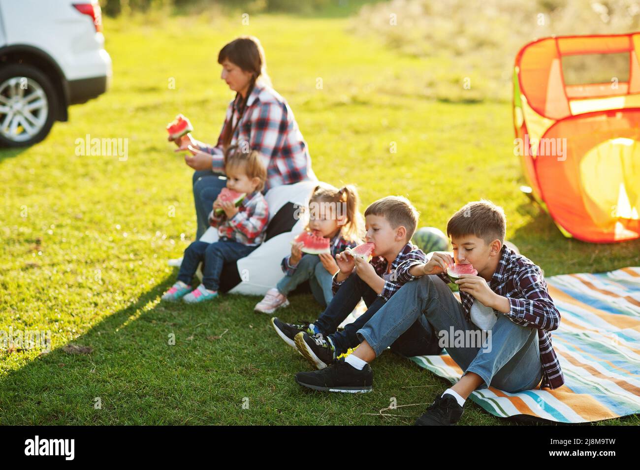 Family spending time together. Four kids with mother eat watermelon ...