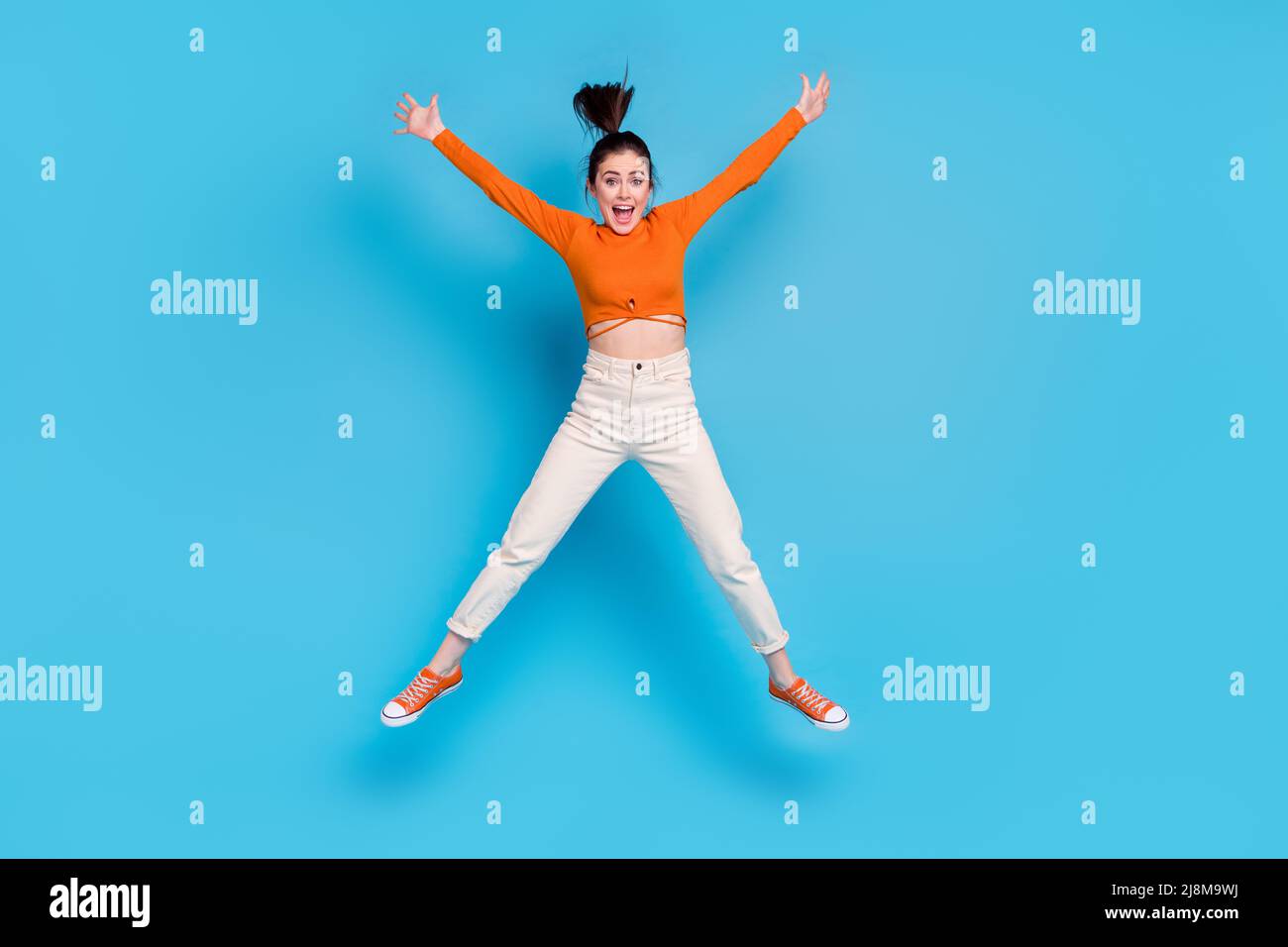 Full body image of cheerful ecstatic woman jumping star pose having fun isolated on blue color ...
