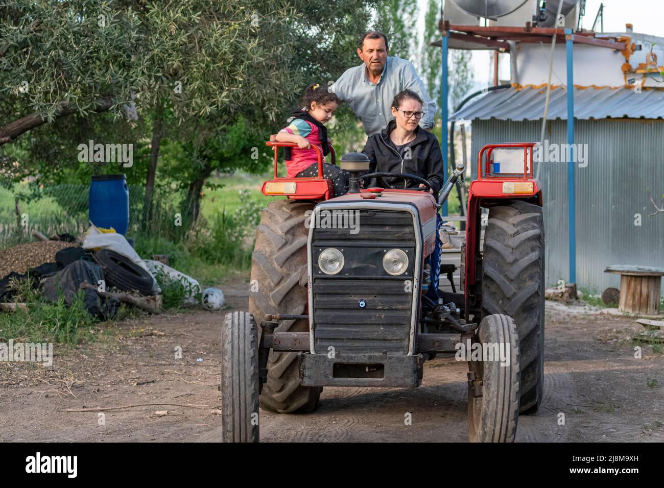 Selective focus shot of mom driving tractor and grandpa and little girl ...