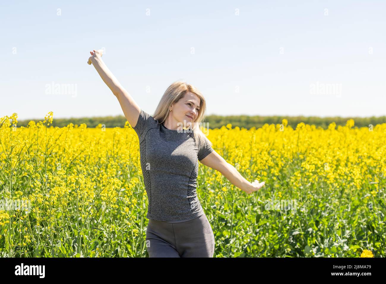 young woman posing in beautiful yellow blooming rapeseed or oilseed rape field. girl holding ...