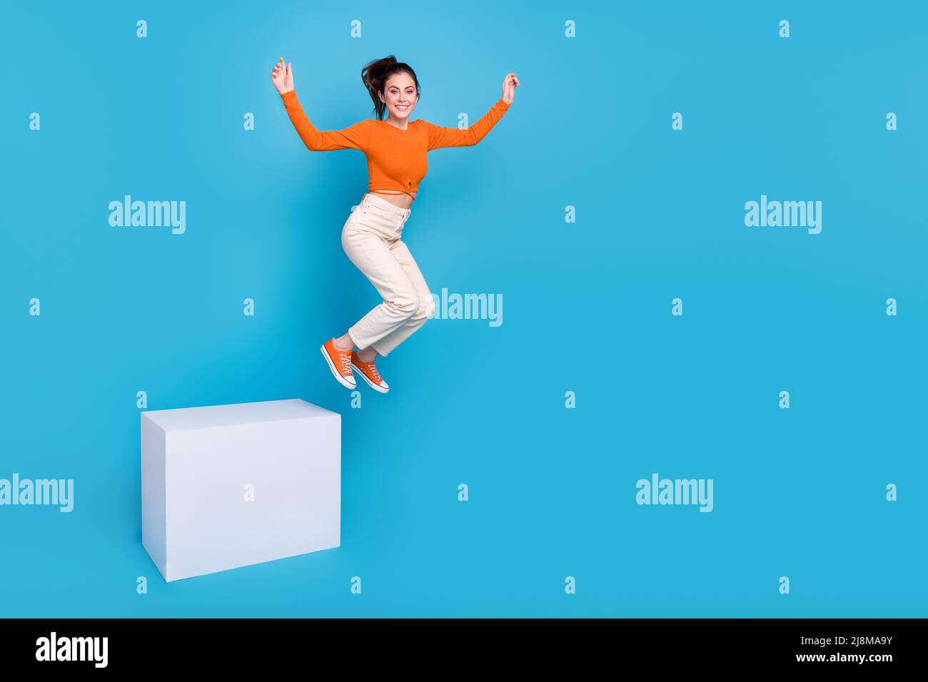 Full size photo of charming good mood female jumping from cube podium ...
