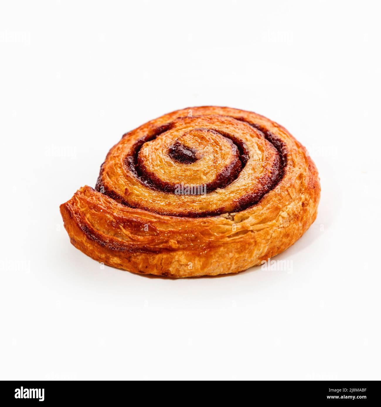 Crispy appetizing snail-bun with cinnamon puff, close-up. White ...