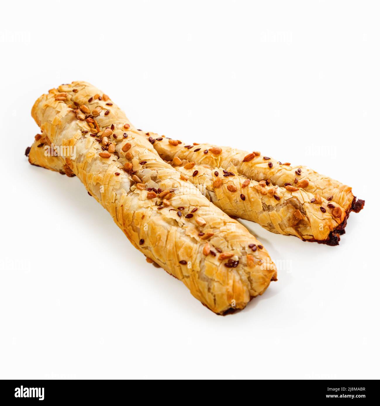 Two crispy appetizing pigtail made of puff pastry with sunflower seeds ...