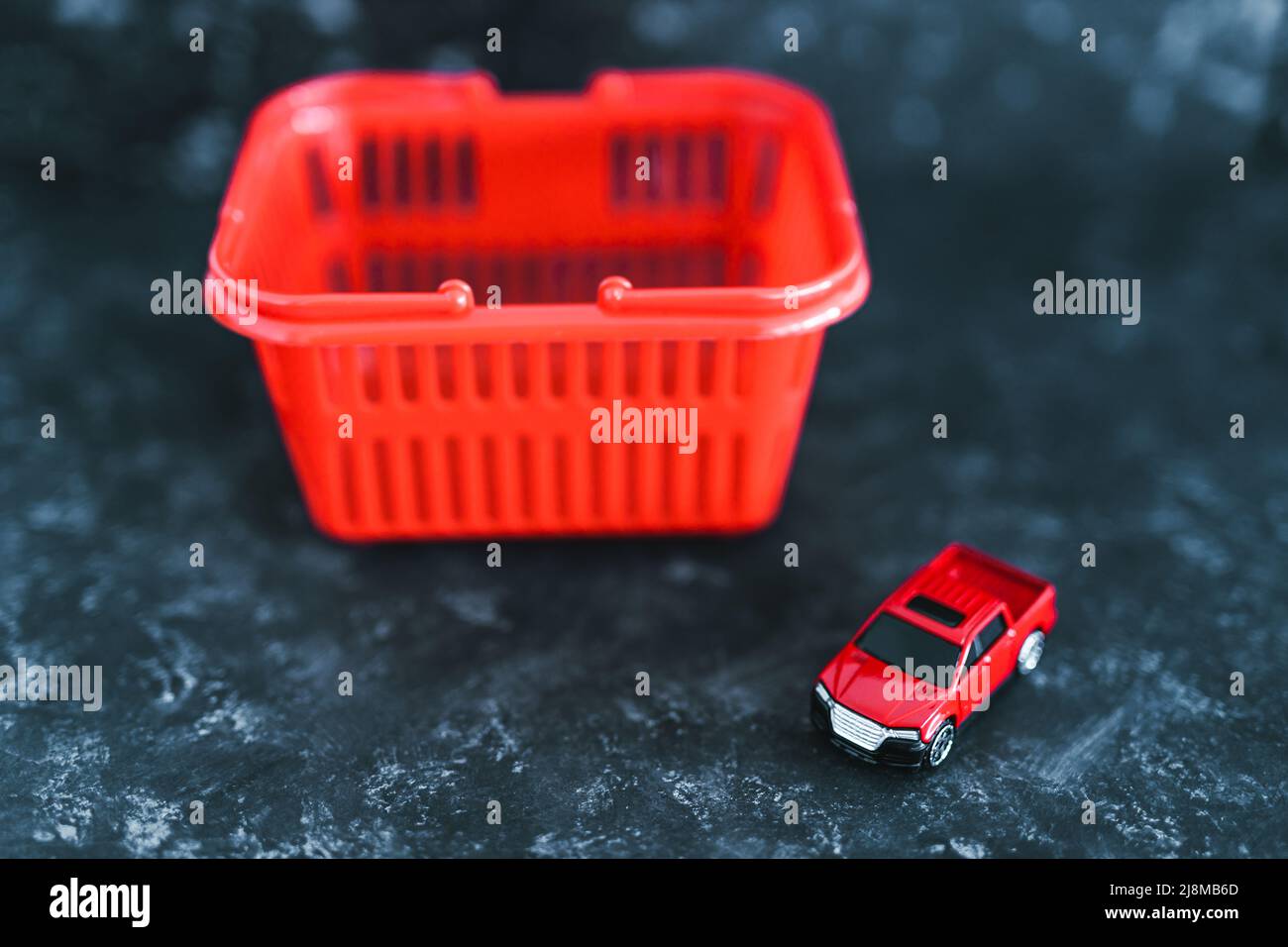 red toy car inside of shopping basket over black marble background ...