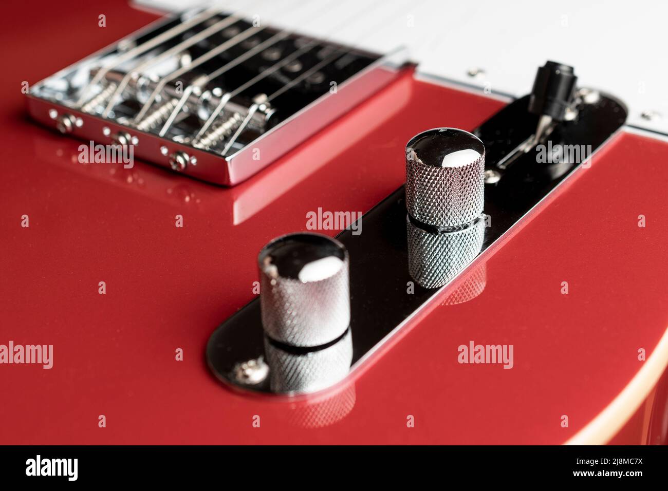 Red guitar control plate and bridge with selective focus on the volume ...