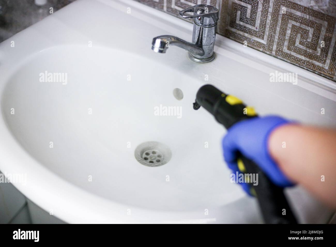 Cleaning and disinfection of the washbasin in the bathroom with hot ...