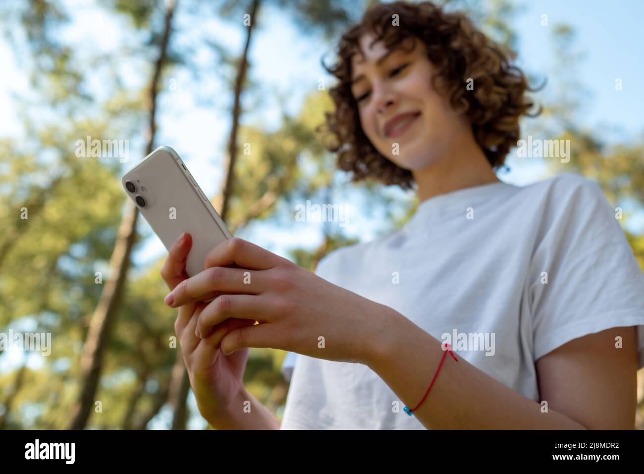 Attractive smiling redhead female wearing white tee holding a smart ...
