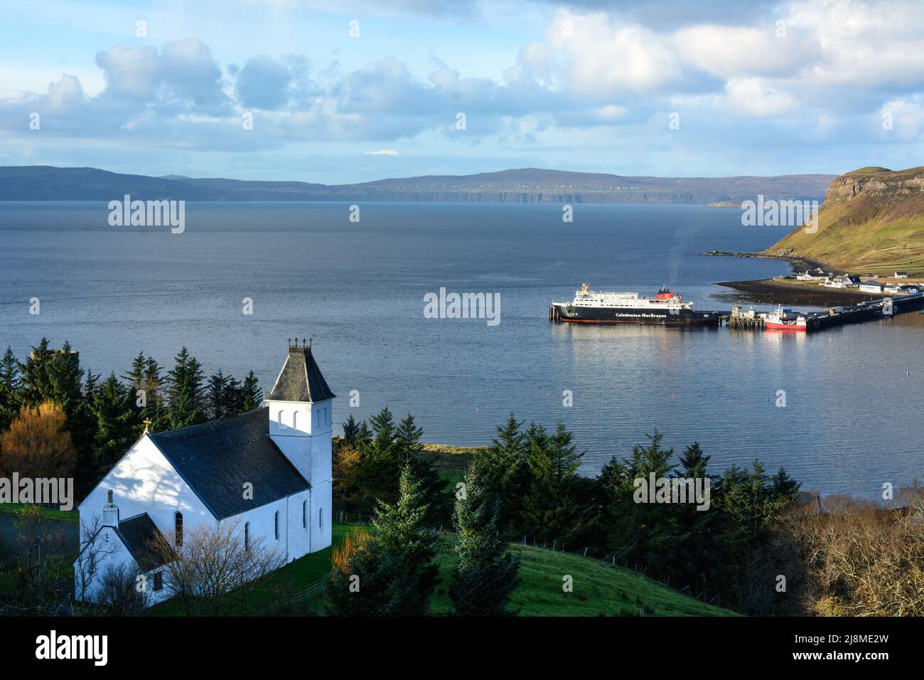 CalMac ferry docked in Uig, Isle of Skye, with church and loch in ...