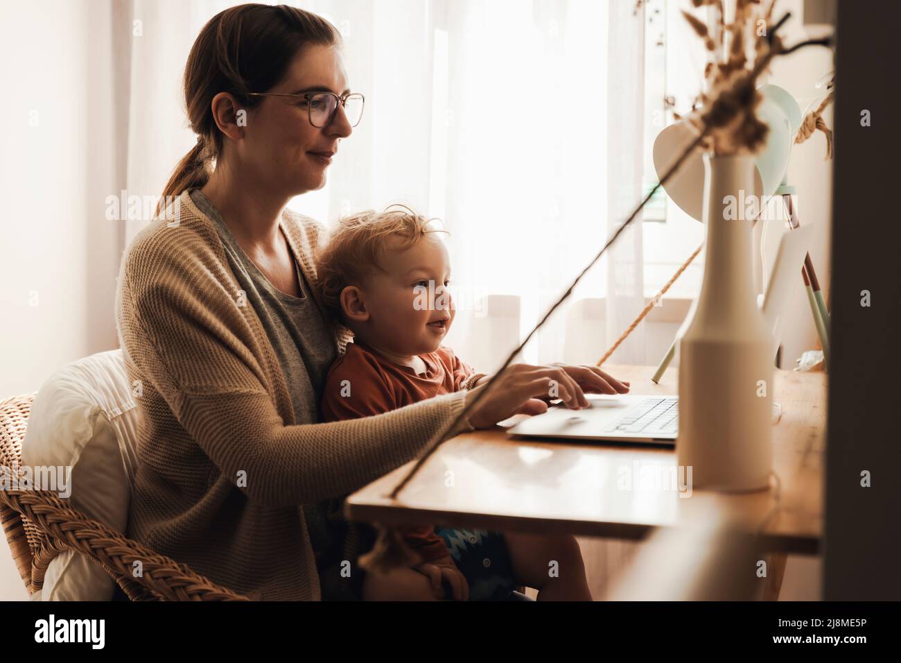 Busy woman working at home with a baby in the lap Stock Photo - Alamy