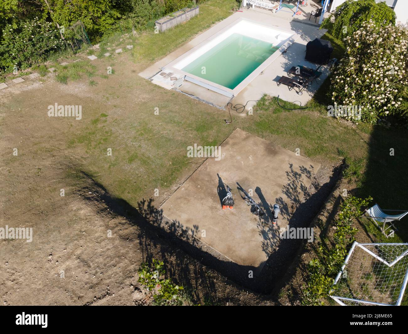 Drone flight over pool in the middle of greenery, fresh grass grown and ...