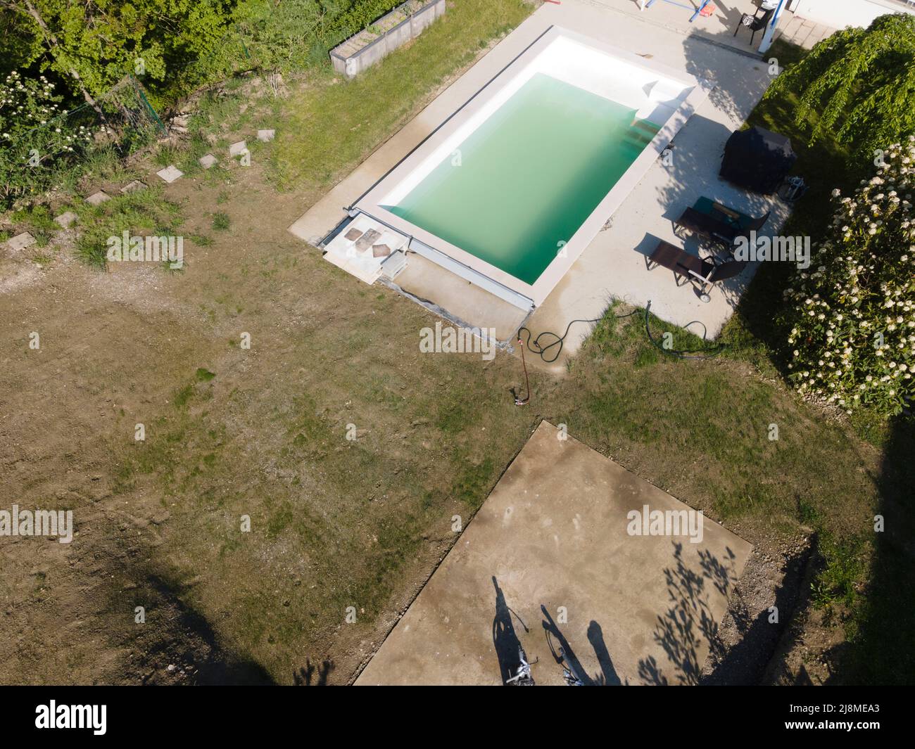 Drone flight over pool in the middle of greenery, fresh grass grown and ...