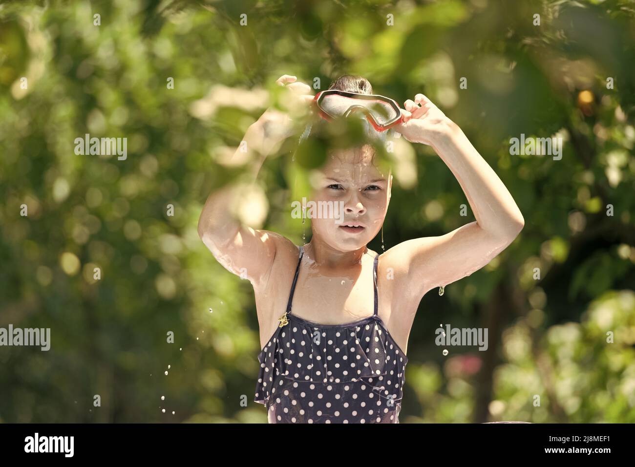 Enjoying a summer day. Wet child take off goggles. Girl go sunbathing ...