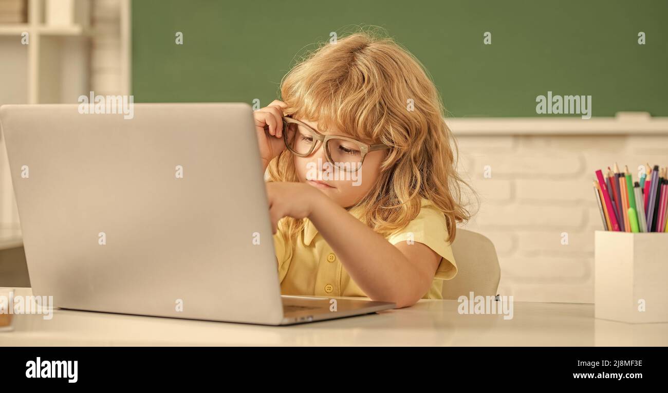 busy kid boy in glasses study online in school classrrom with computer ...