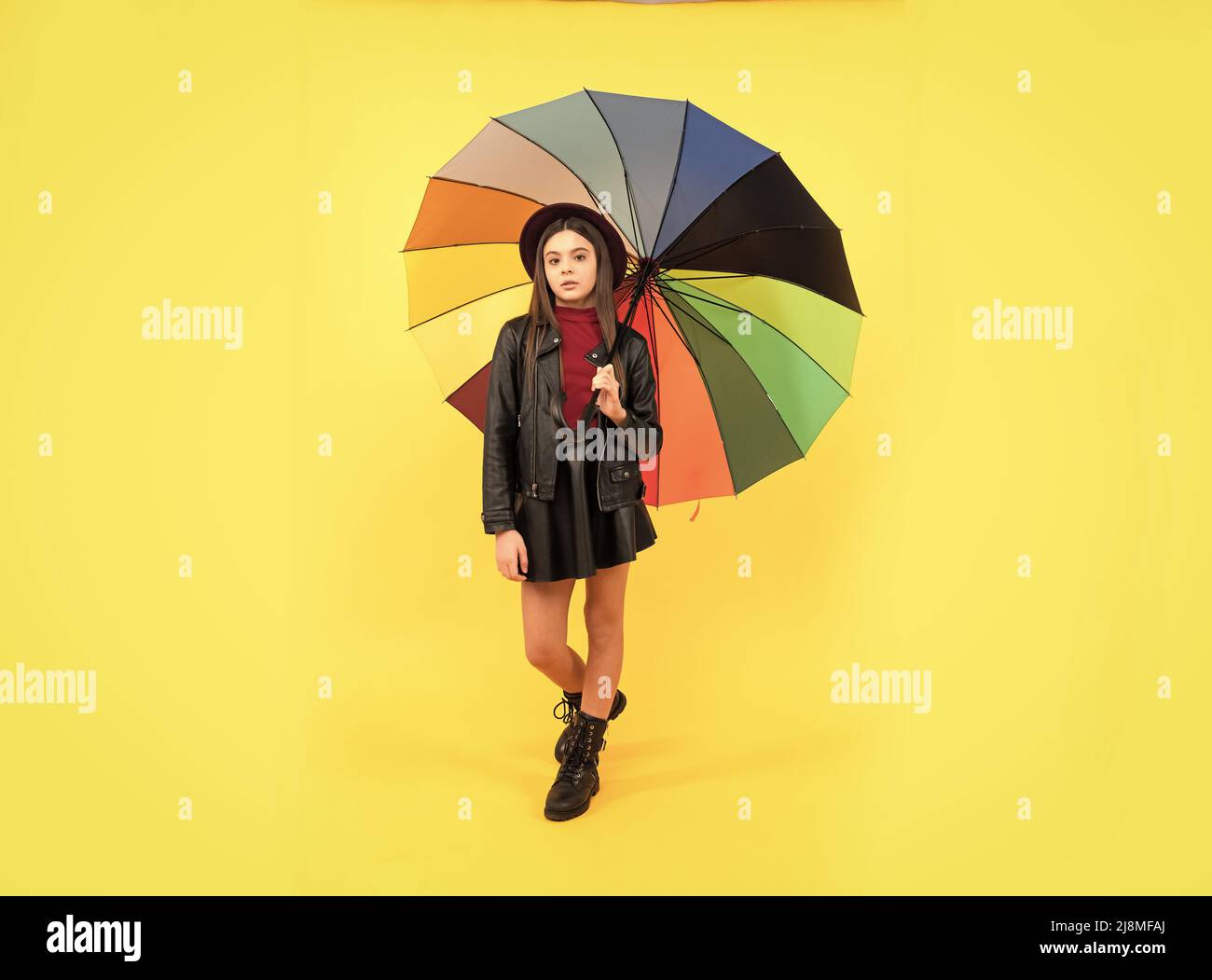 happy teen girl in hat and leather clothes under rainbow umbrella ...
