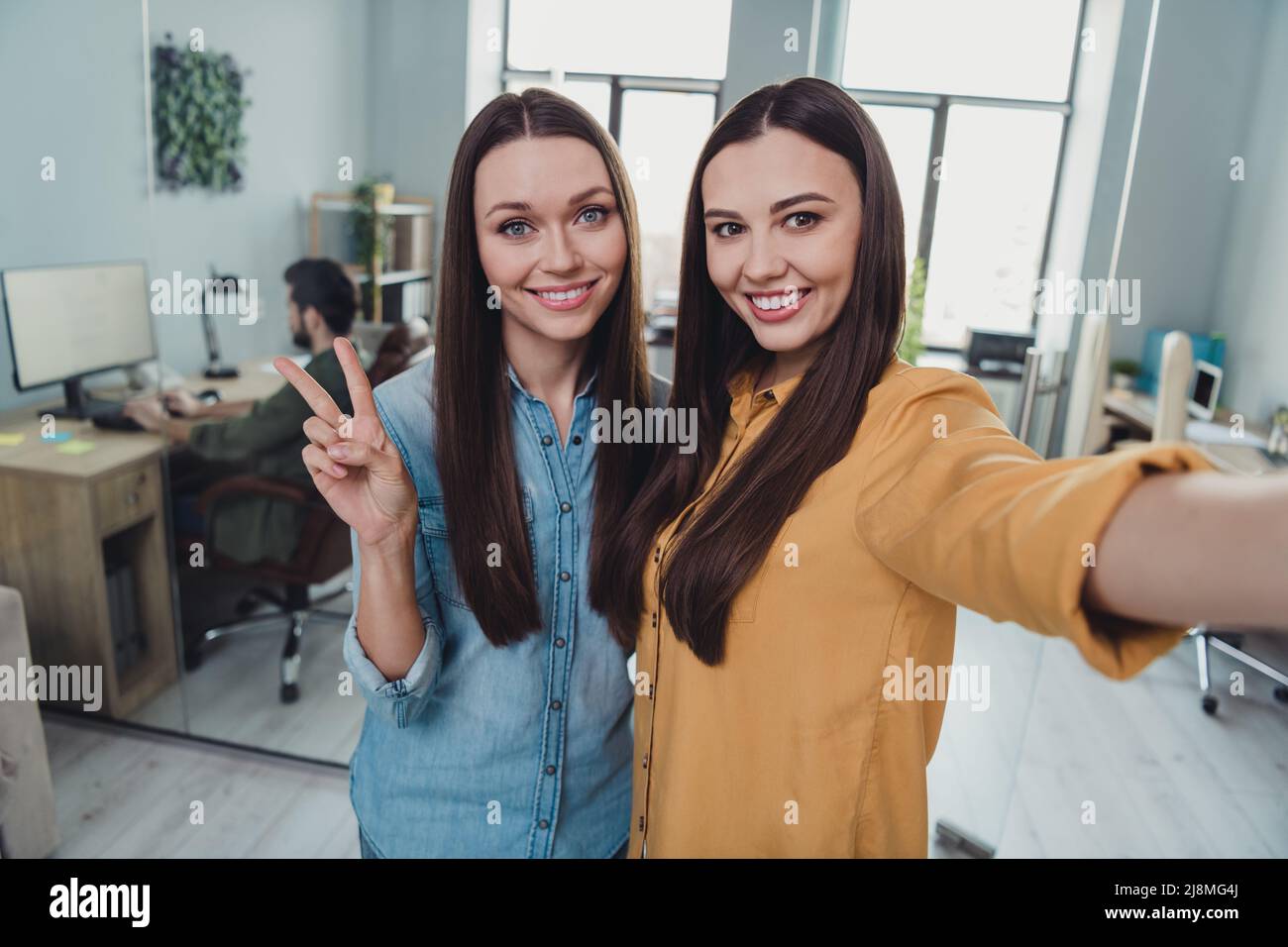 Portrait of two beautiful cheerful girls experts friends showing v-sign ...