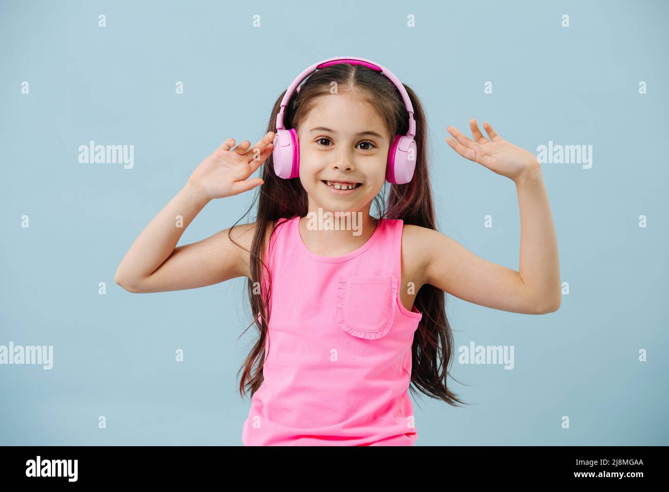 Cute tween girl in pink shirt and wireless headphones over blue ...