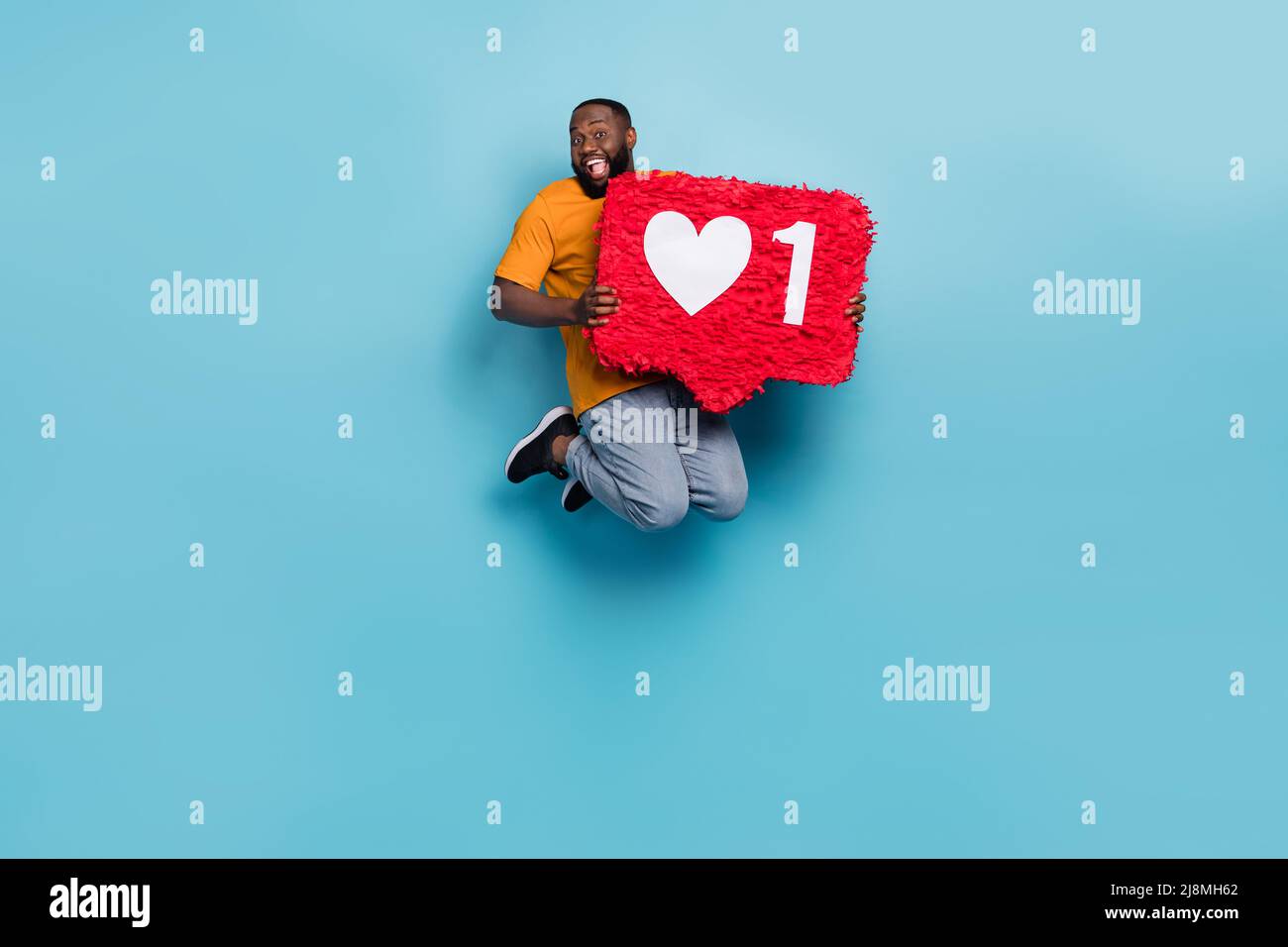 Photo of pretty shocked guy wear orange t-shirt jumping high holding ...