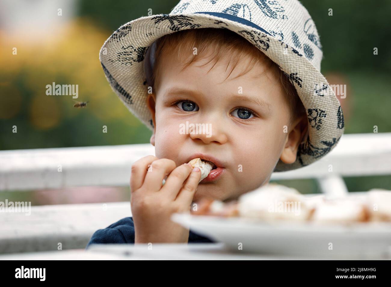 Little boy eating toasted bread for breakfast on green colour garden ...