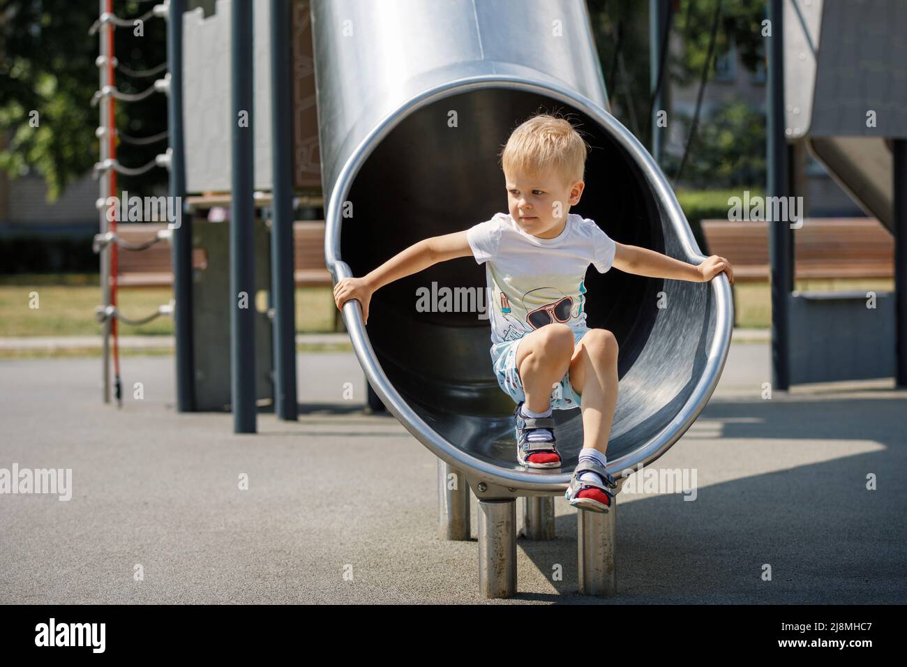 Joyful kid playing in tube slide on children's playground Stock Photo ...