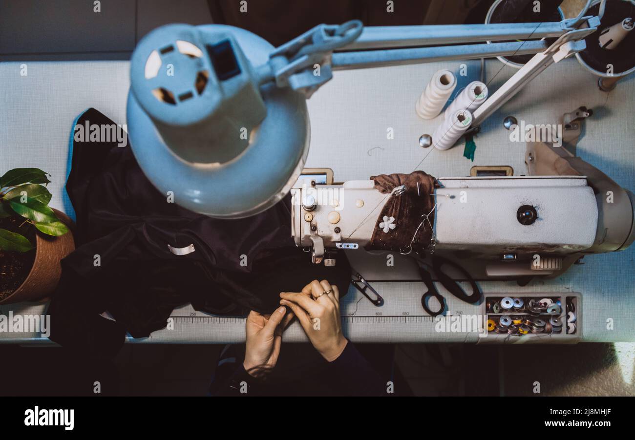 A woman tailor sews clothes - a fashionable jacket made of velvet ...