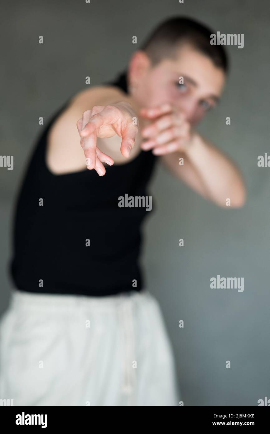 non binary peeping through hands, in an uncertain way Stock Photo - Alamy