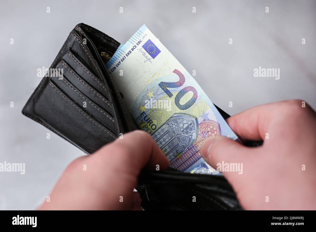 Takes out a 20 euro banknote from a leather wallet on a light ...