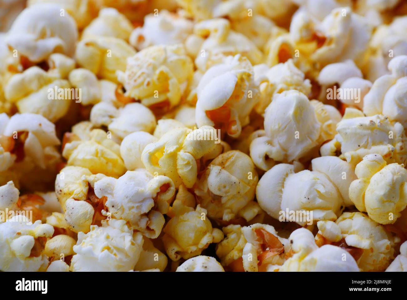 popcorn spilling from a container on red background Stock Photo - Alamy