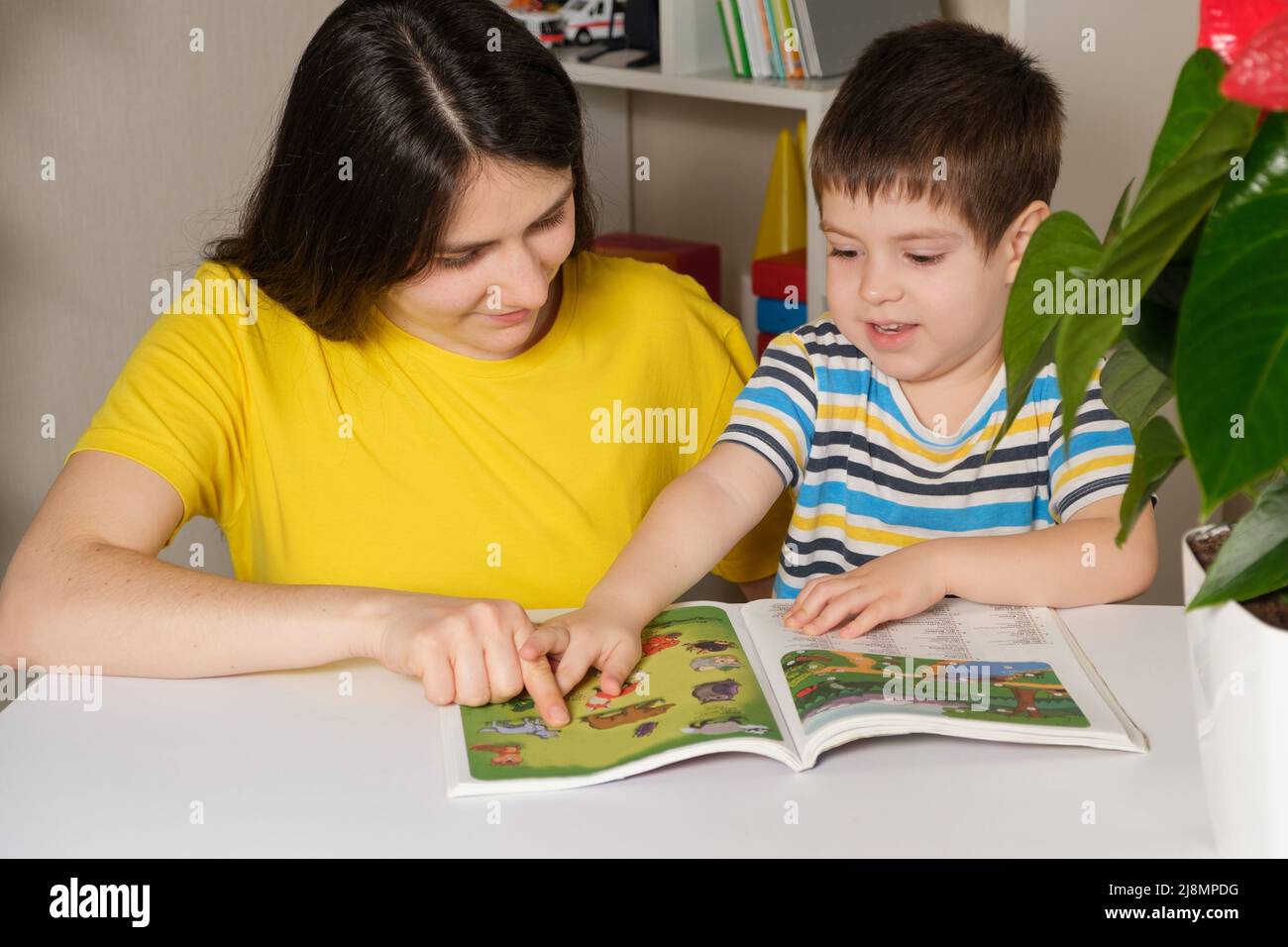 Mother and son read the book, look at the pictures on the pages ...