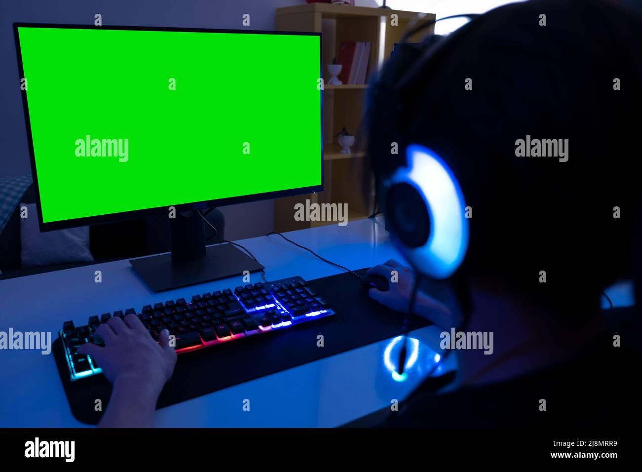 Blurred green computer screen, selective focus on teenage who is using ...