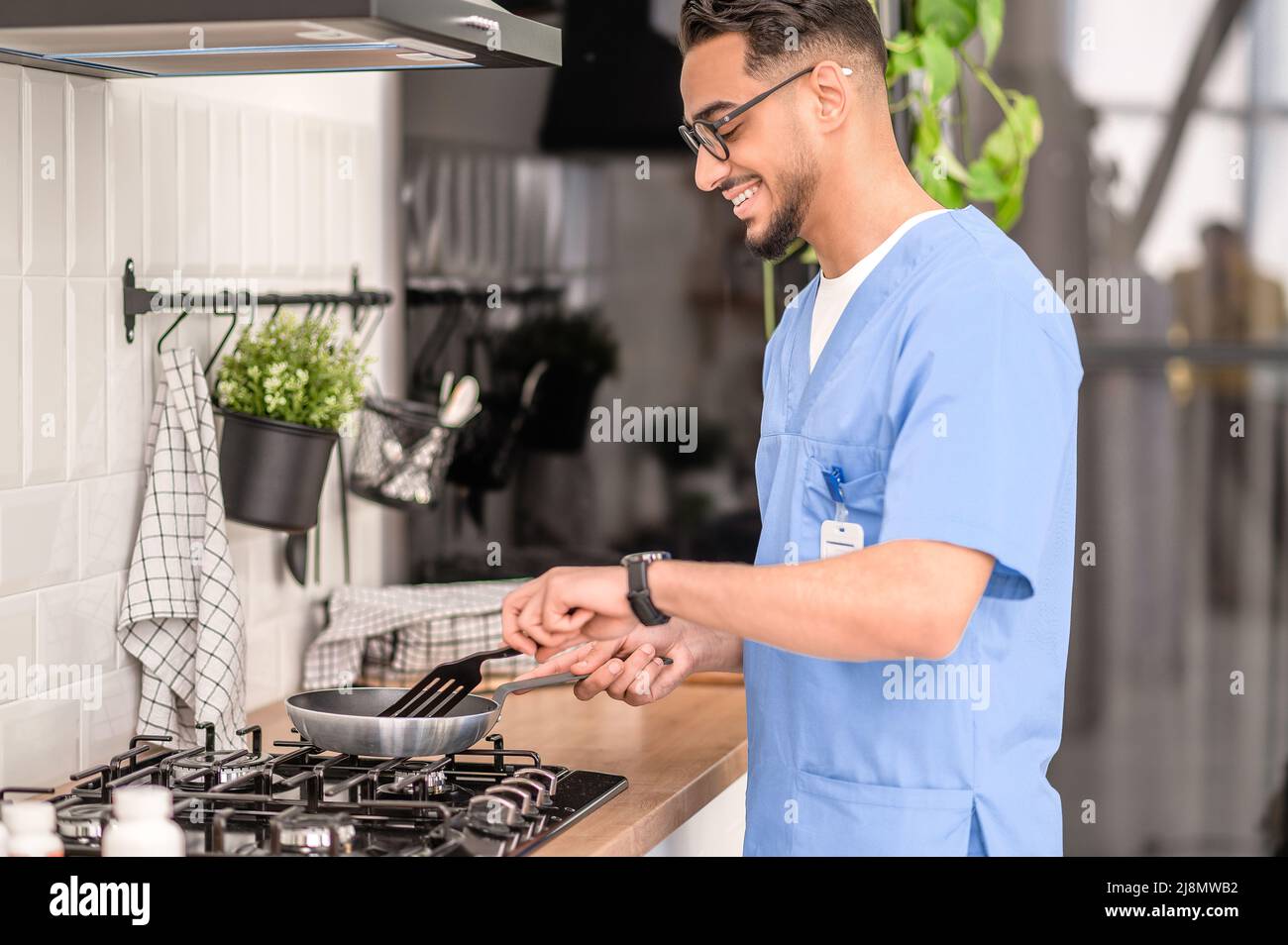 Smiling young man cooking on the gas stove Stock Photo - Alamy