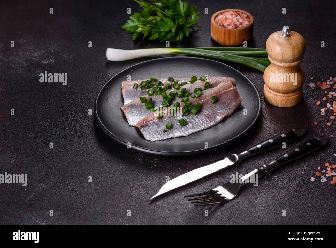 Delicious fresh herring fillet with salt, spices and herbs on a black ...